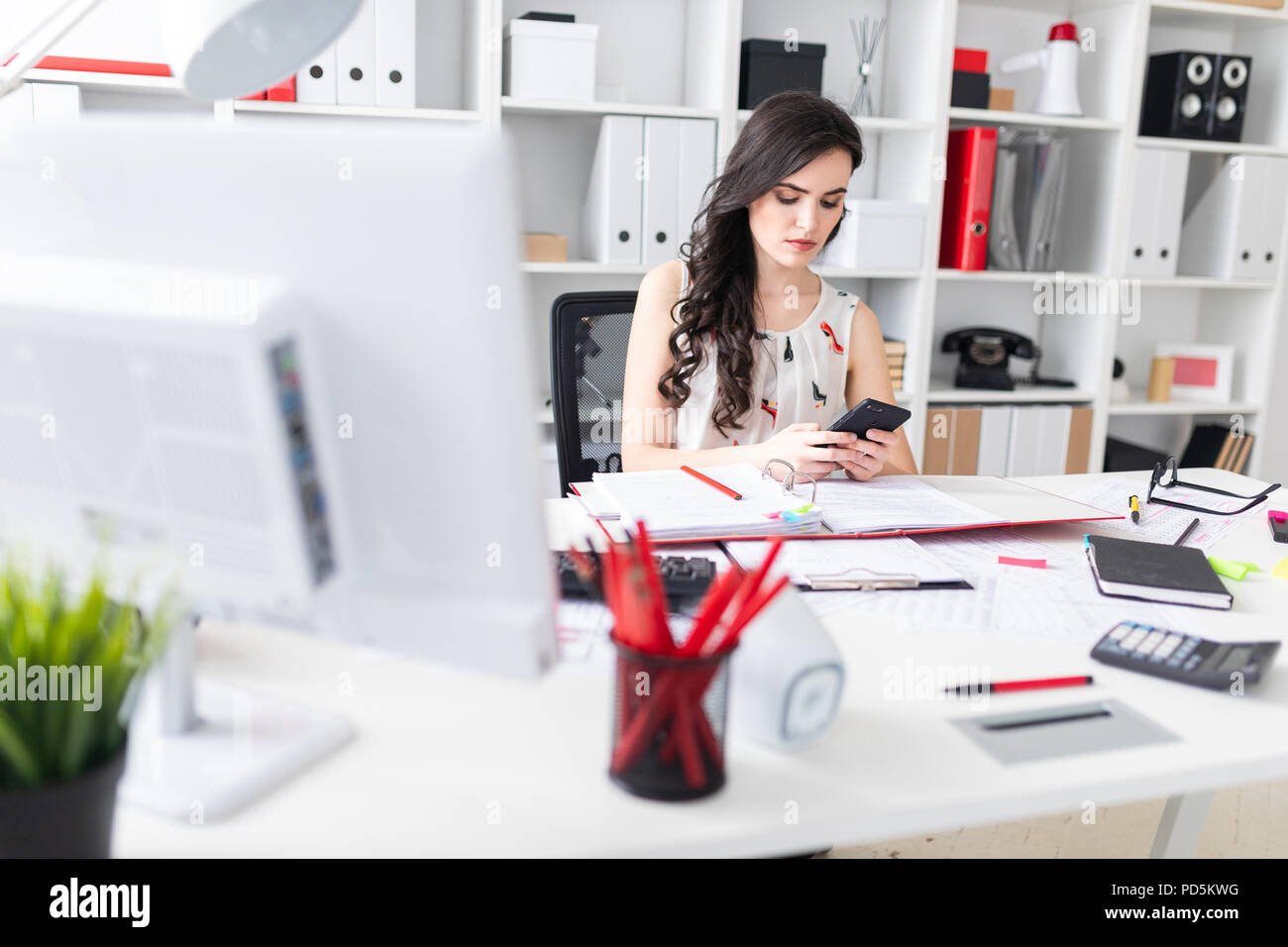 Young girl in office typing text in phone Stock Photo - Alamy