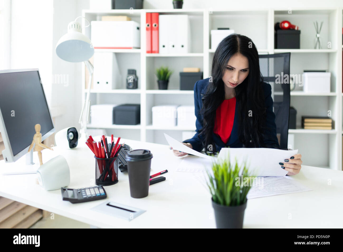 Beautiful young girl is looking through documents, sitting in the ...