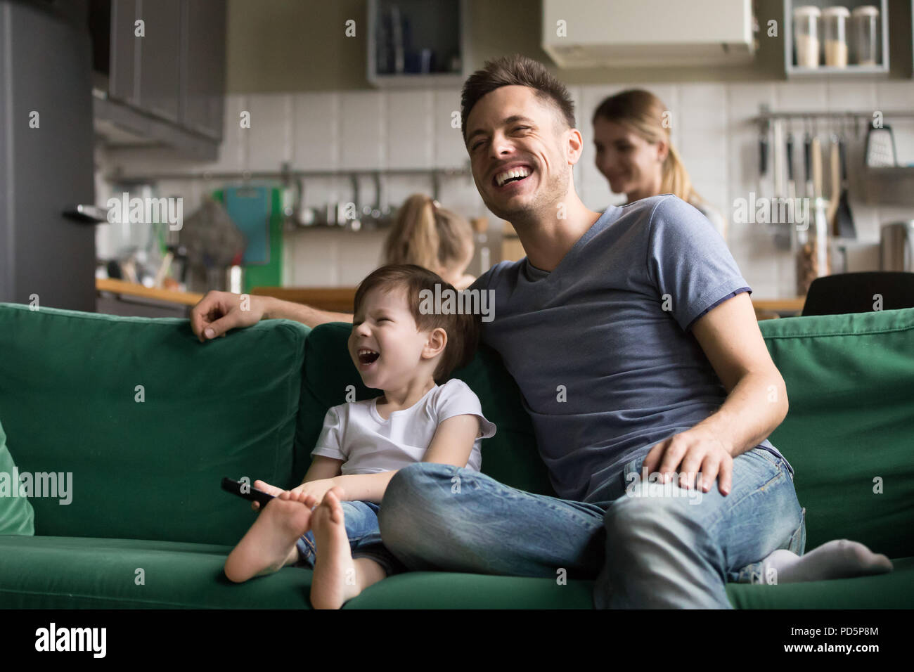Happy dad and kid son laughing watching tv together Stock Photo - Alamy