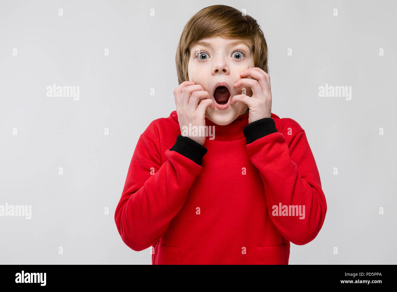 Cute puzzled astonished little boy with open mouth on grey background ...