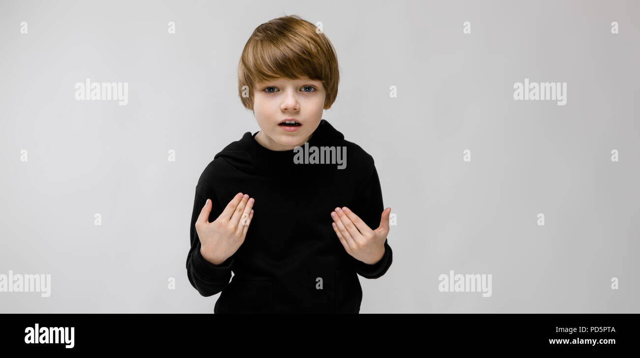 Portrait of adorable surprised little boy standing in studio on grey ...