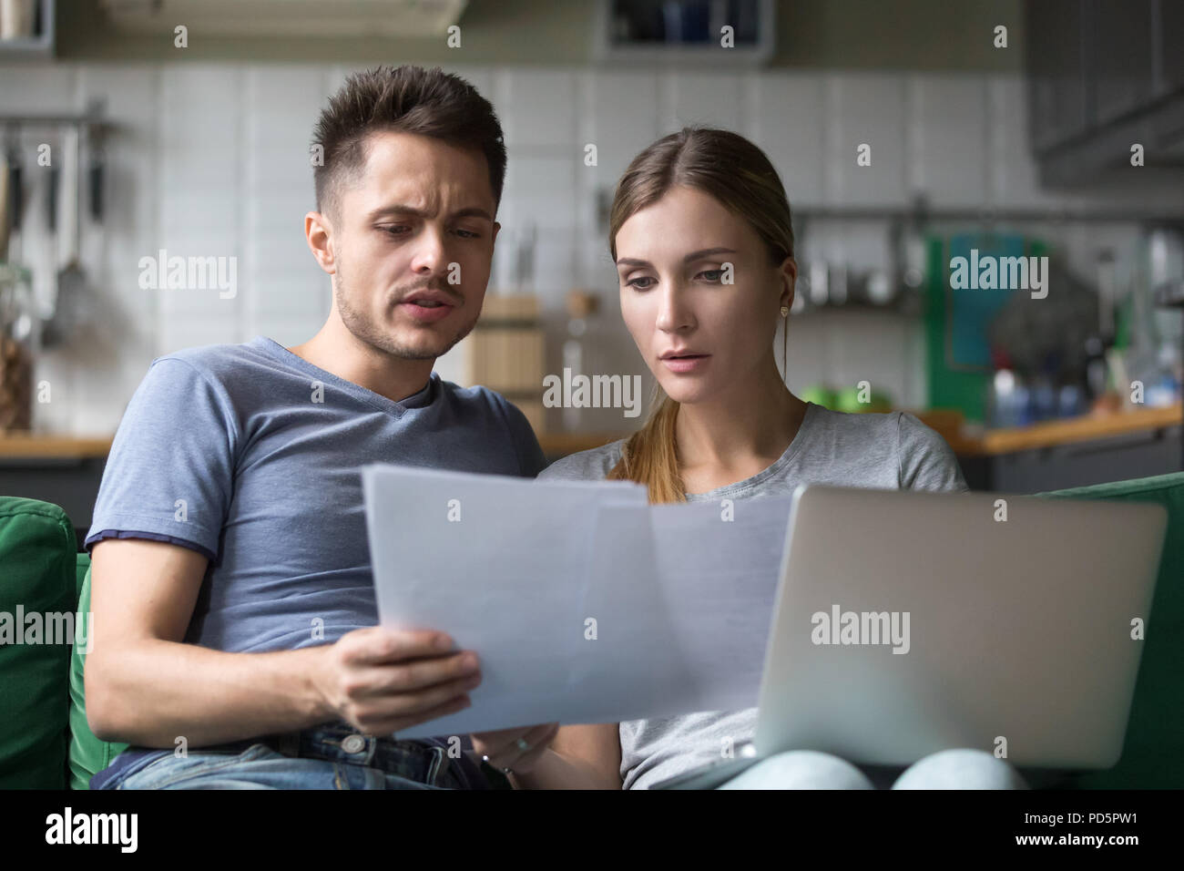 Serious confused couple checking domestic bills with papers and Stock ...