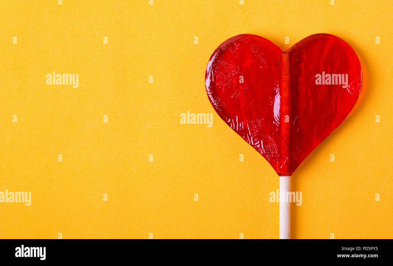 One candy heart shape on yellow background Stock Photo - Alamy