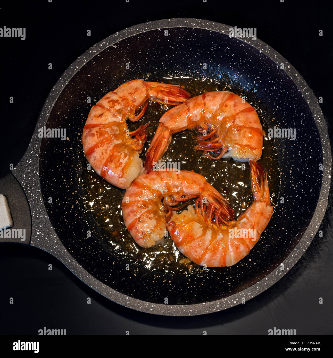 Tiger shrimps fry in oil on a black frying pan Stock Photo - Alamy