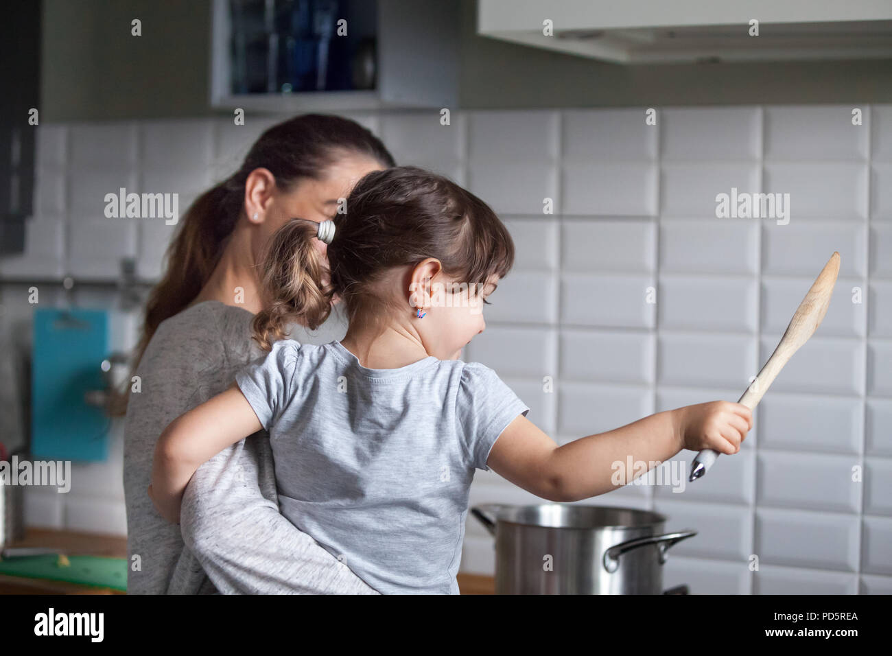 Rear view at mother holding child daughter helping to cook Stock Photo ...