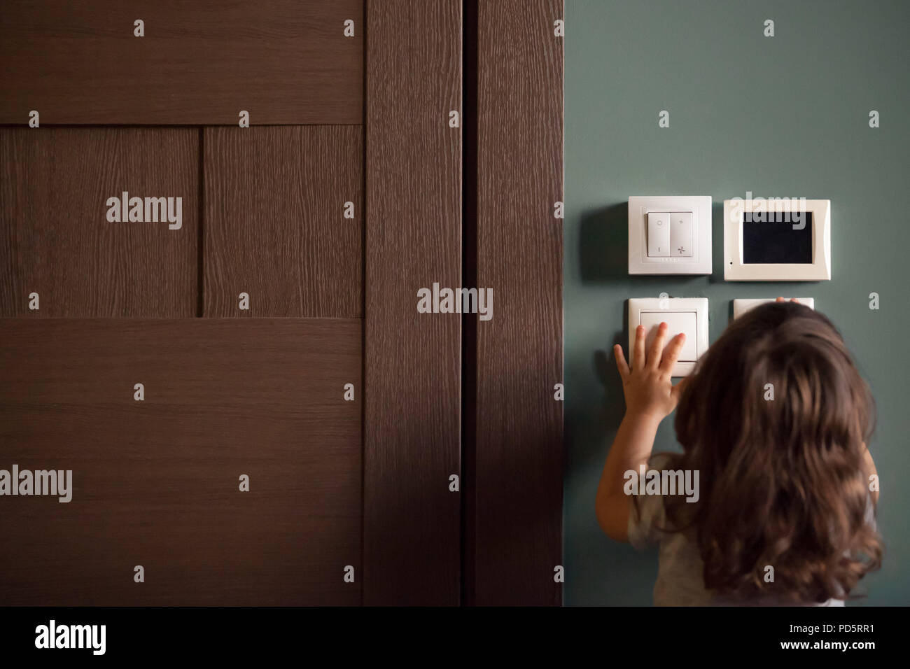 Rear view at little child girl playing turning light switches Stock ...
