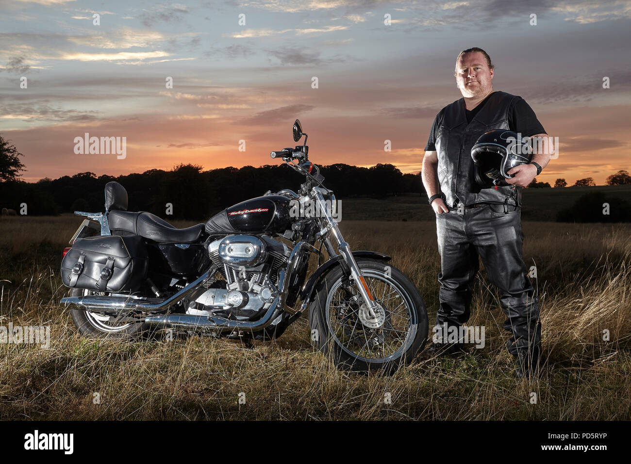 Leather clad biker posing for a photoshoot on his custom Harley ...