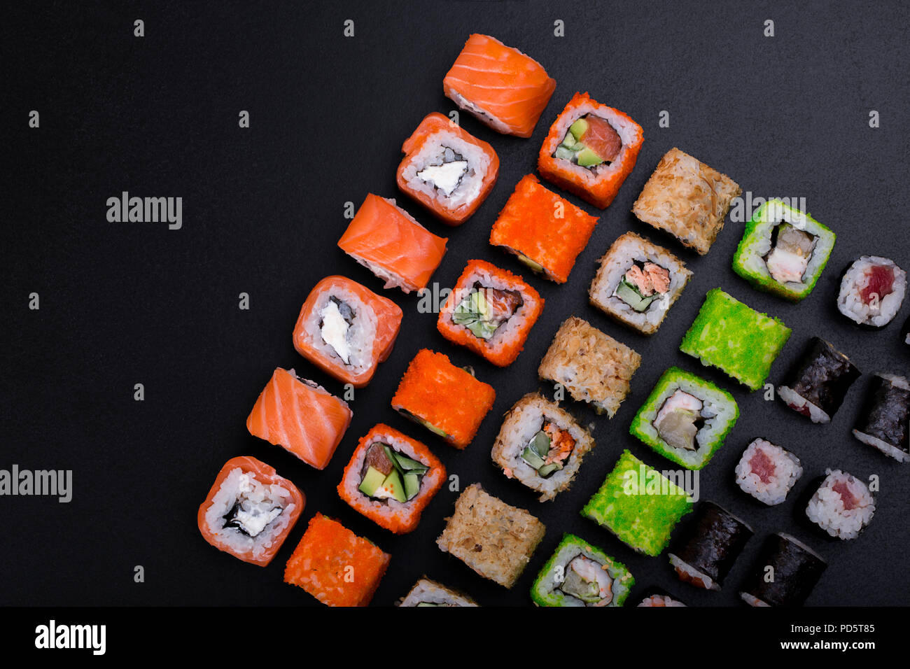 Japanese sushi rolls in the shape of a line on black background top ...
