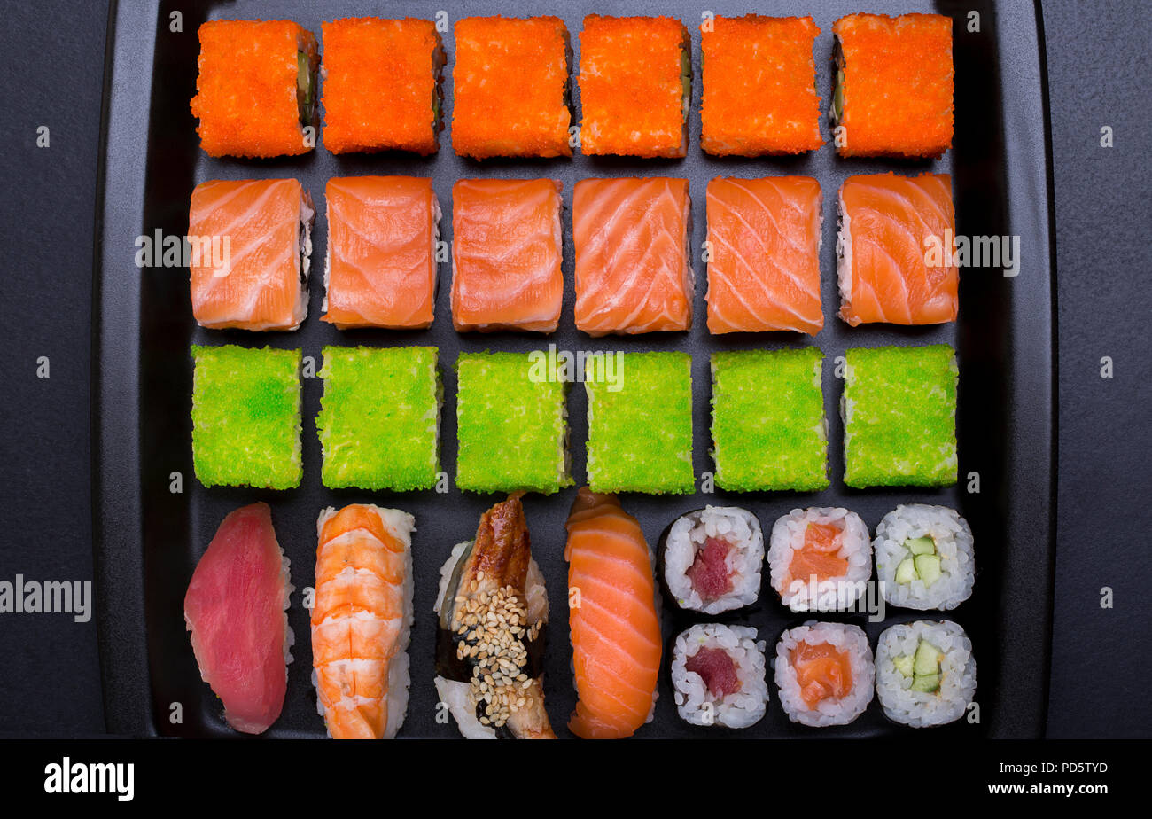 Japanese sushi rolls in the shape of a line on black plate background ...
