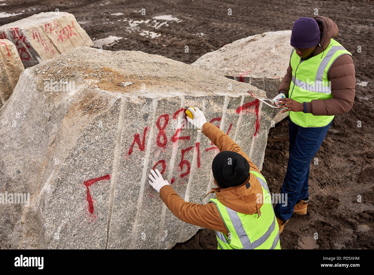 High angle of two industrial workers wearing reflective jacket marking ...