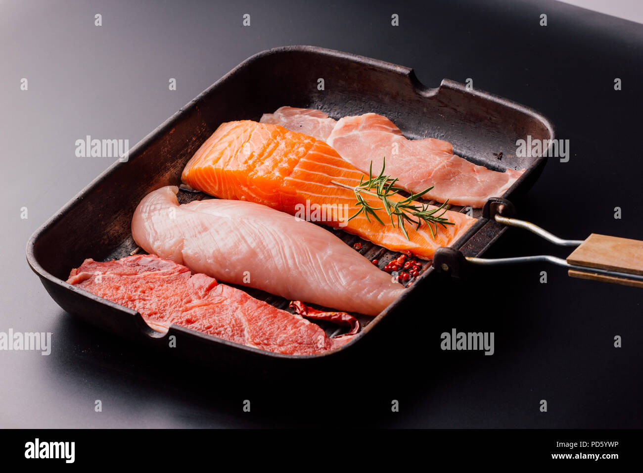Group of animal proteins, chicken, meat, fish and pork on a black ...