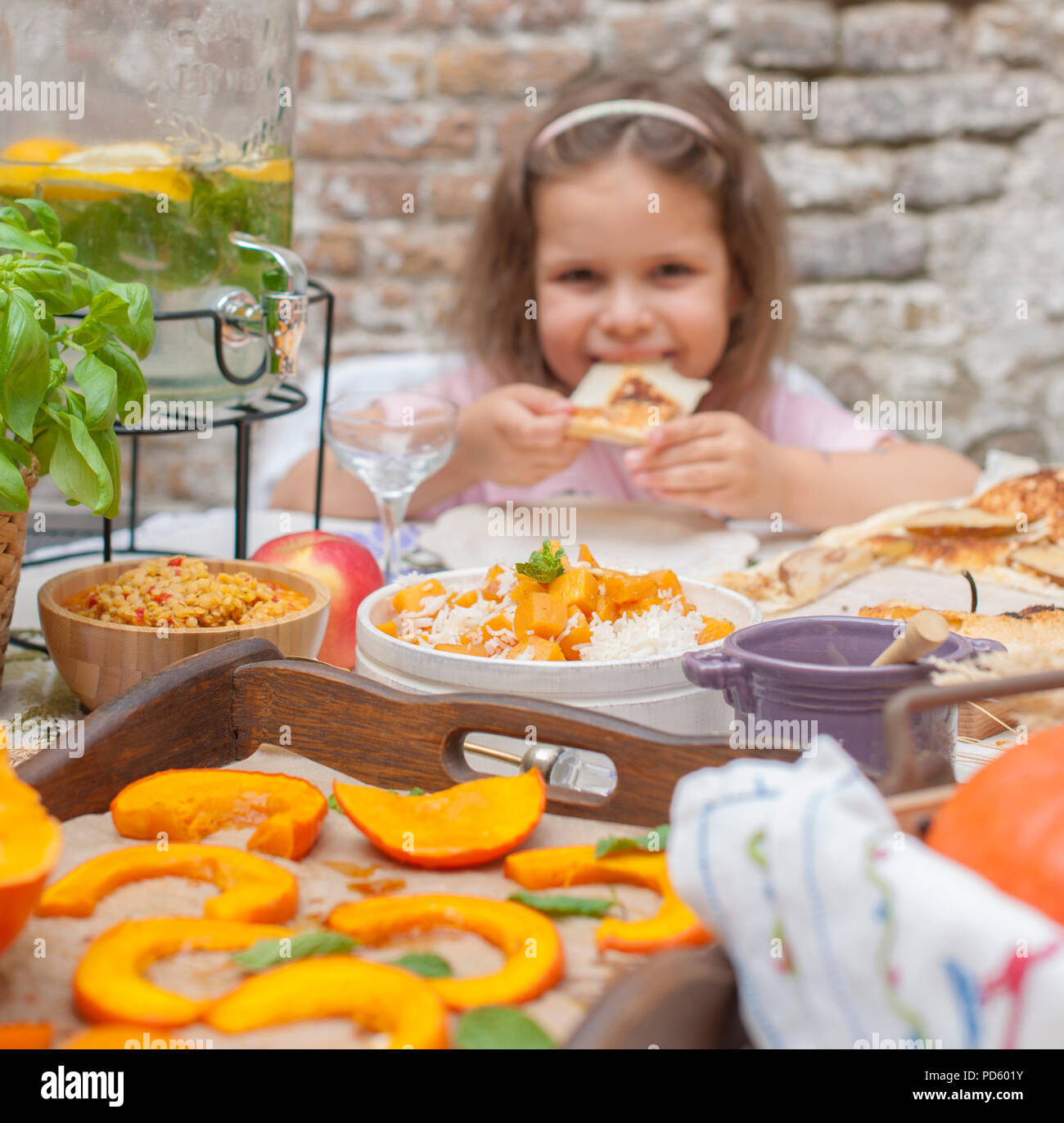 Little girl is eating pie. Family dinner in the courtyard outdoors ...