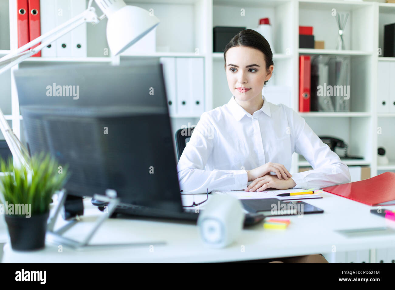 A young girl is sitting at the computer desk in the office Stock Photo ...