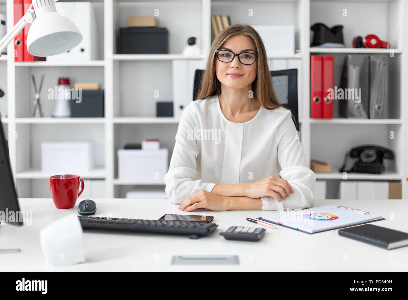 A young girl is sitting at the computer desk in the office Stock Photo ...