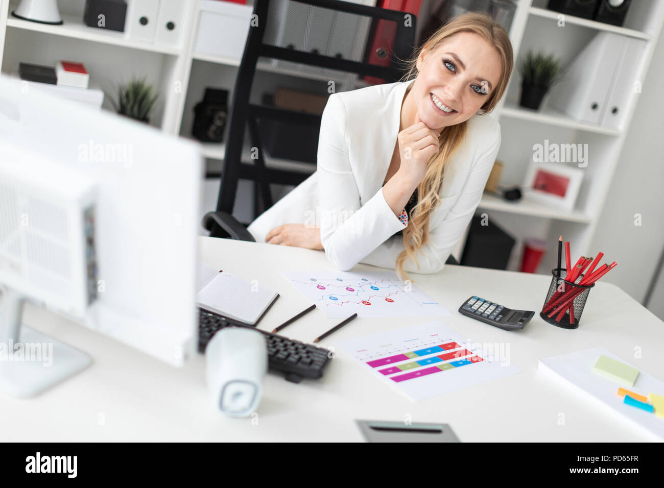 A young girl is sitting at the computer desk in the office Stock Photo ...