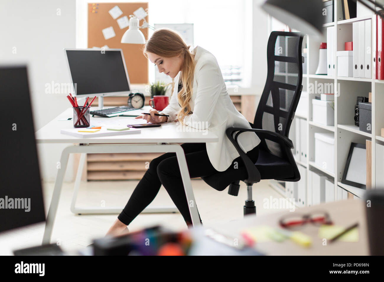 A young girl sits at a computer desk in the office and counts on a ...