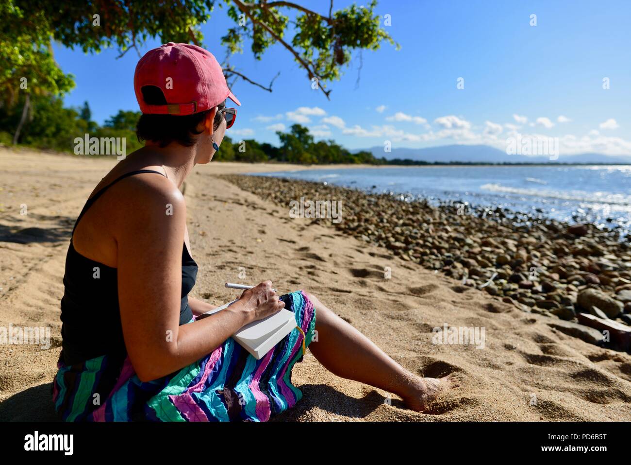 Woman writing a book on the beach, Coastal scenes from tropical north ...
