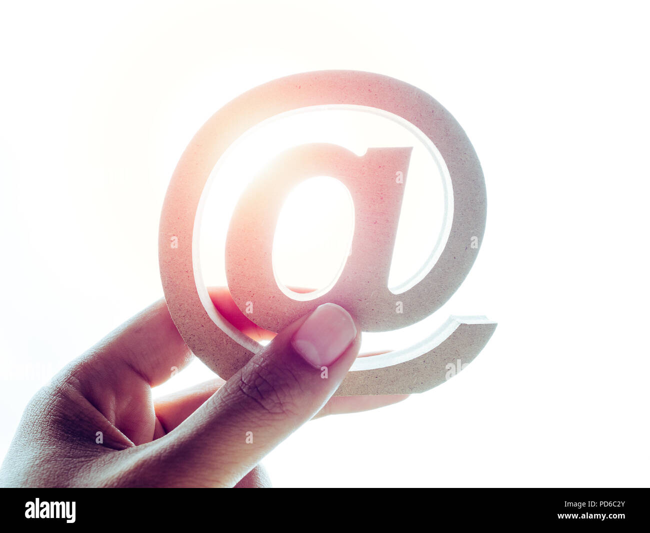 Hand holding wooden E-mail address symbol, arroba icon with light ...