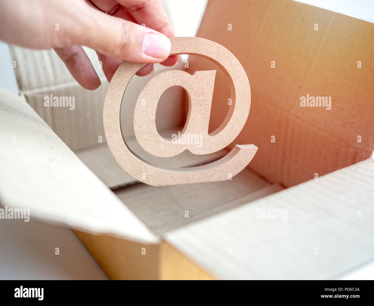 Hand picking wooden E-mail address symbol from the brown paper box ...