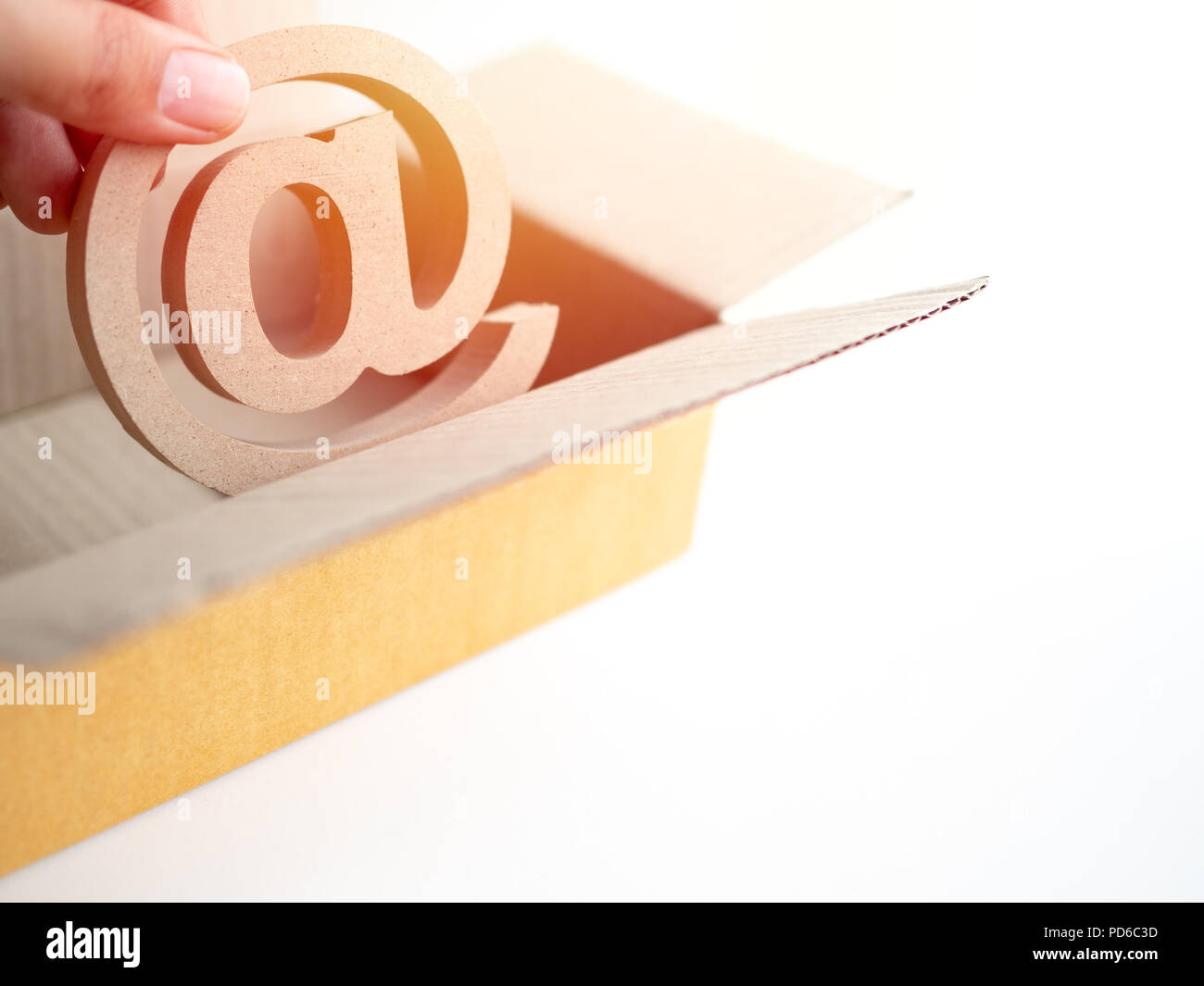Hand picking wooden E-mail address symbol from the brown paper box ...