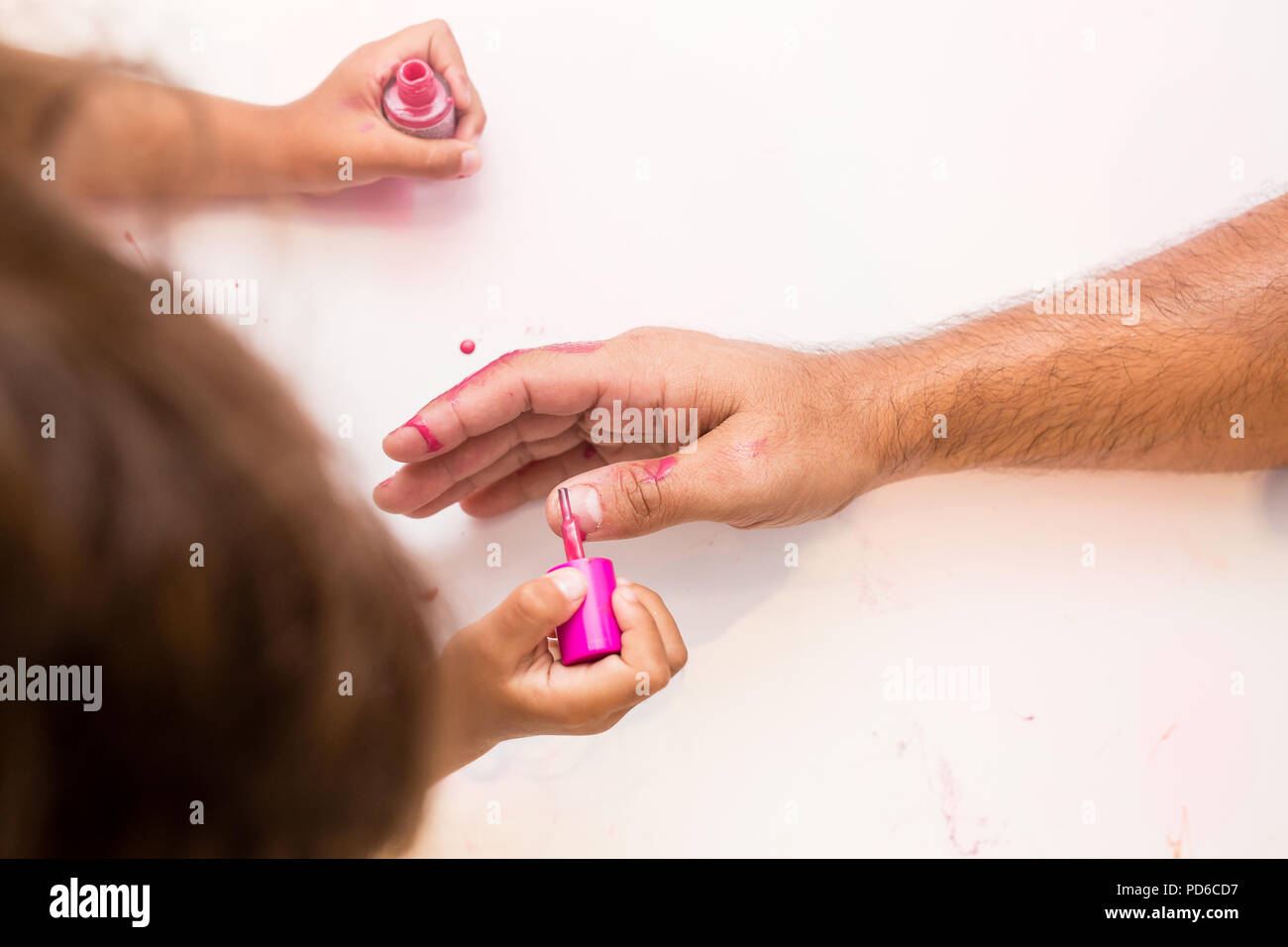 Girl painting fathers nails pink, missing the nails and painting the ...