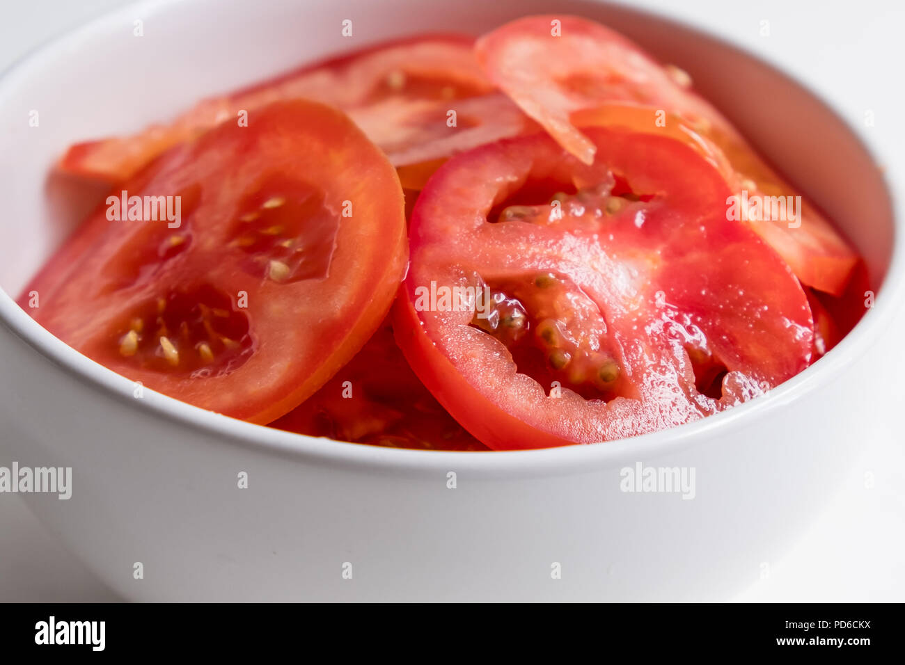 top view of sliced tomatoes in white bowl on white counter top Stock ...