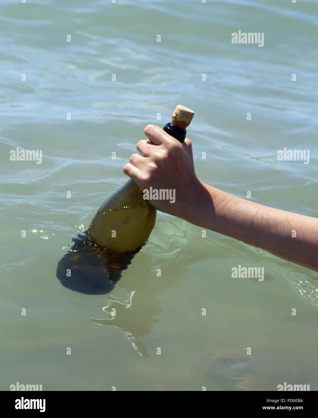 hand collecting the bottle with the secret message from the water of ...