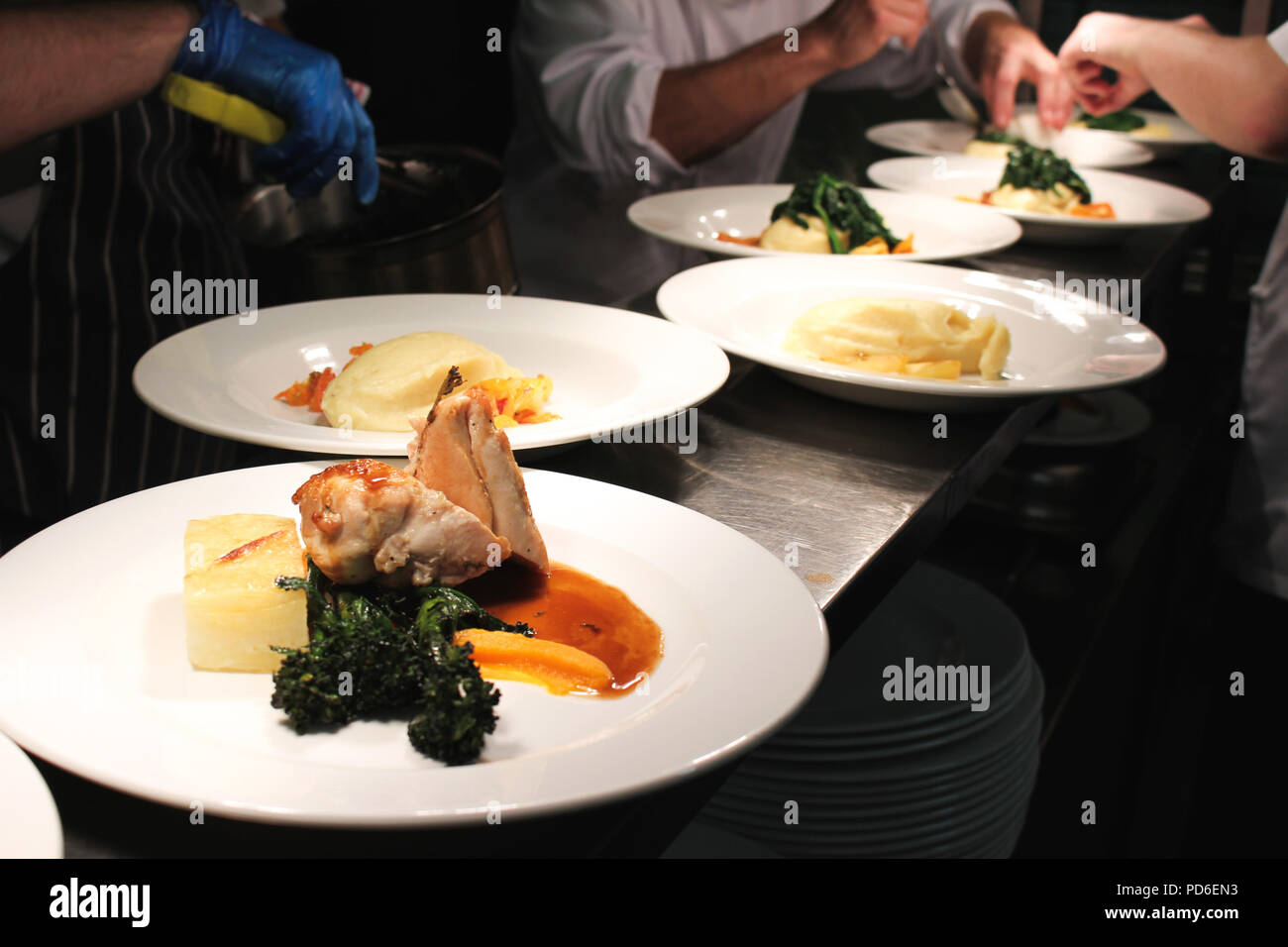 preparing plated food at the kitchen pass Stock Photo - Alamy