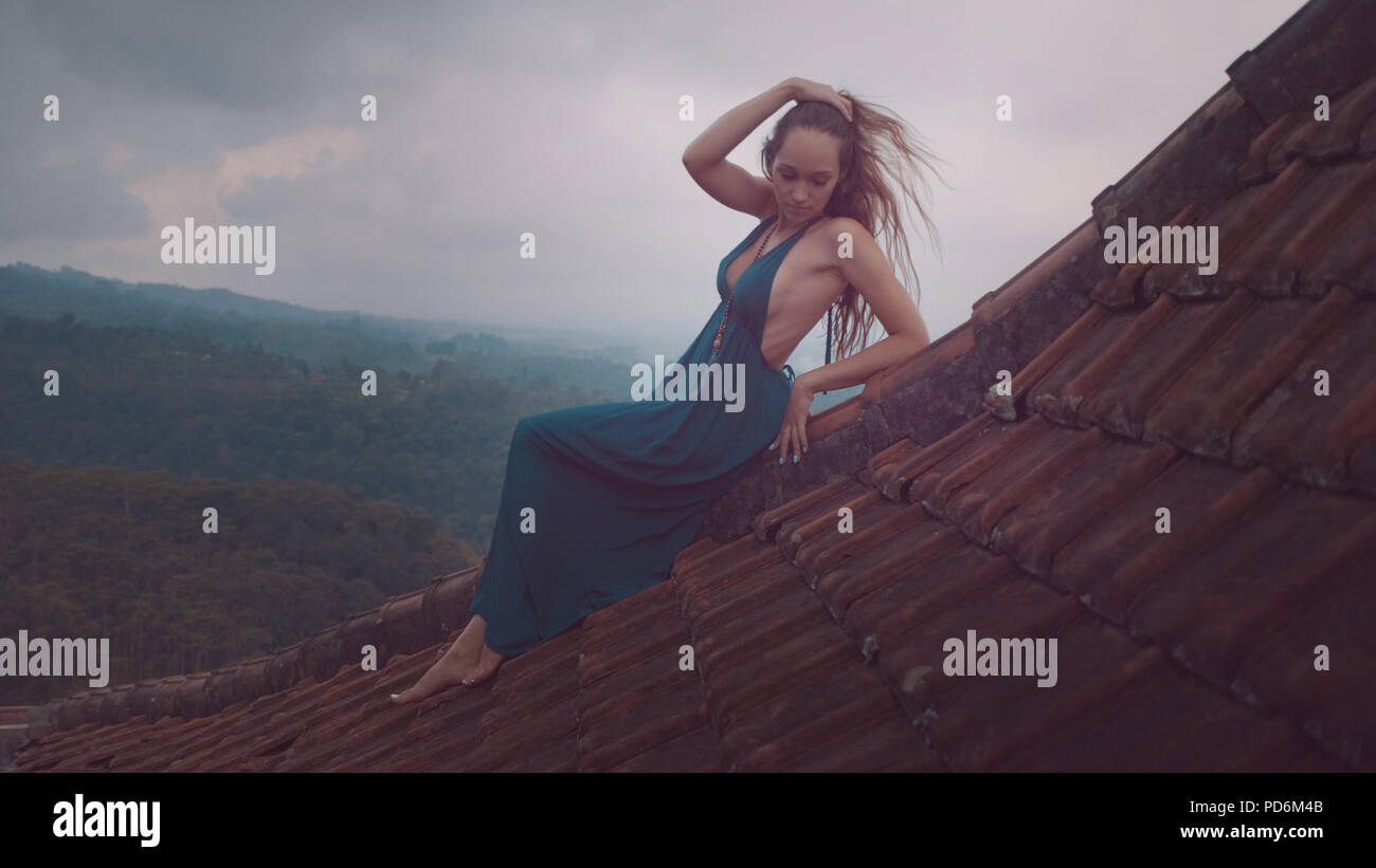 Aerial drone view of beautiful woman in long blue dress sitting on ...