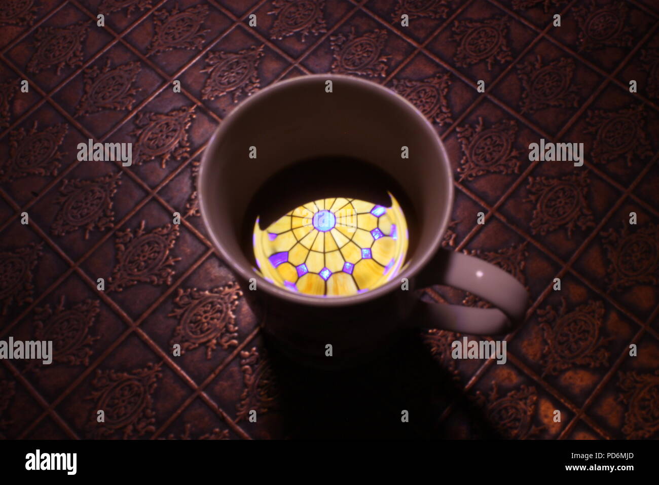 Cup of tea showing reflection of a stained glass window in the roof ...