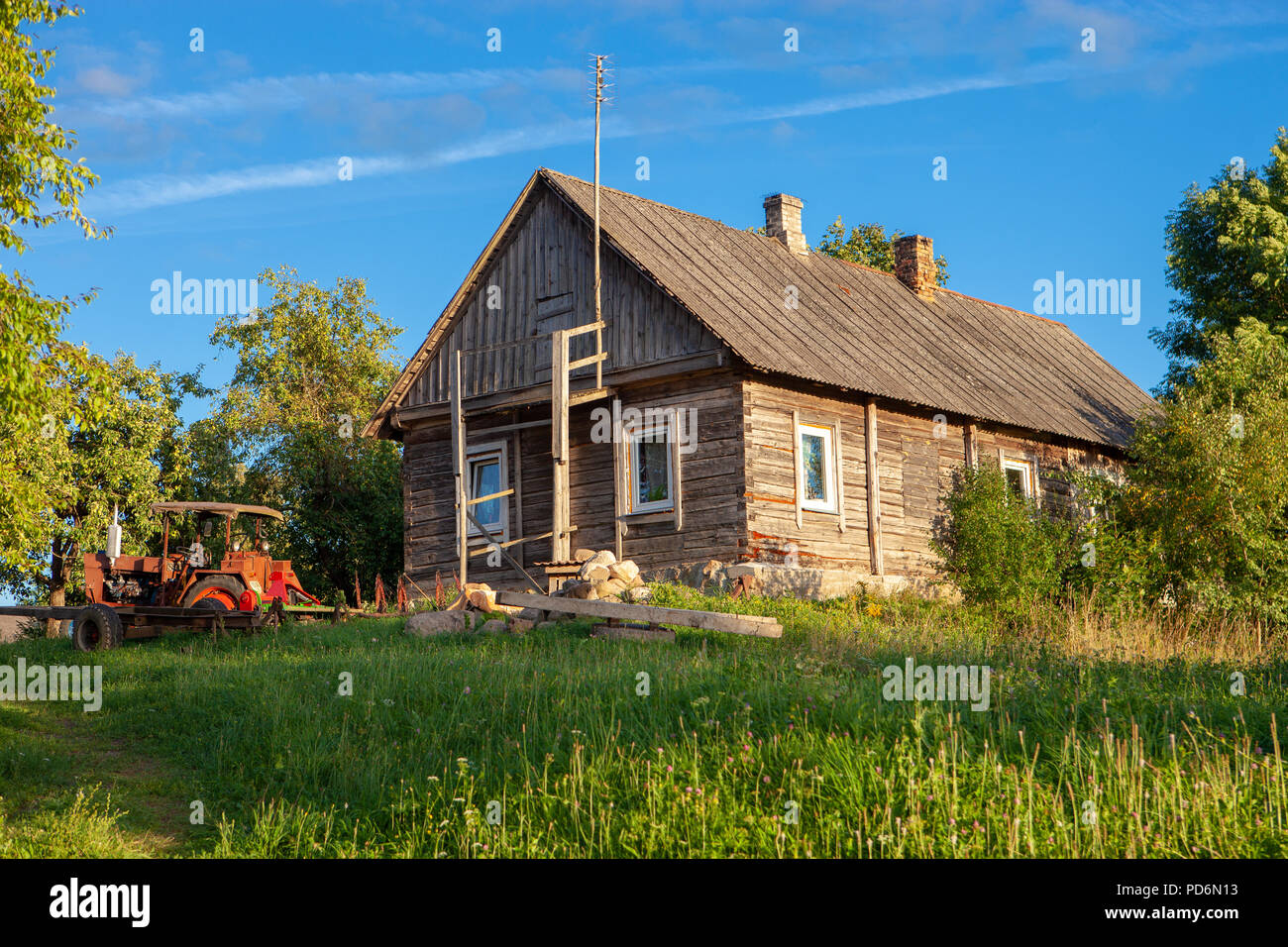Typical Lithuanian wooden house with old tractor in the countryside on ...