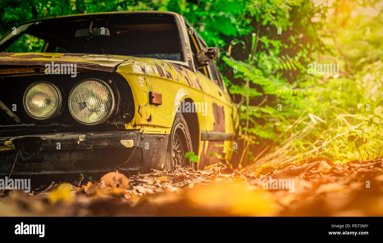 Old wrecked car in vintage style. Abandoned rusty yellow car in the ...