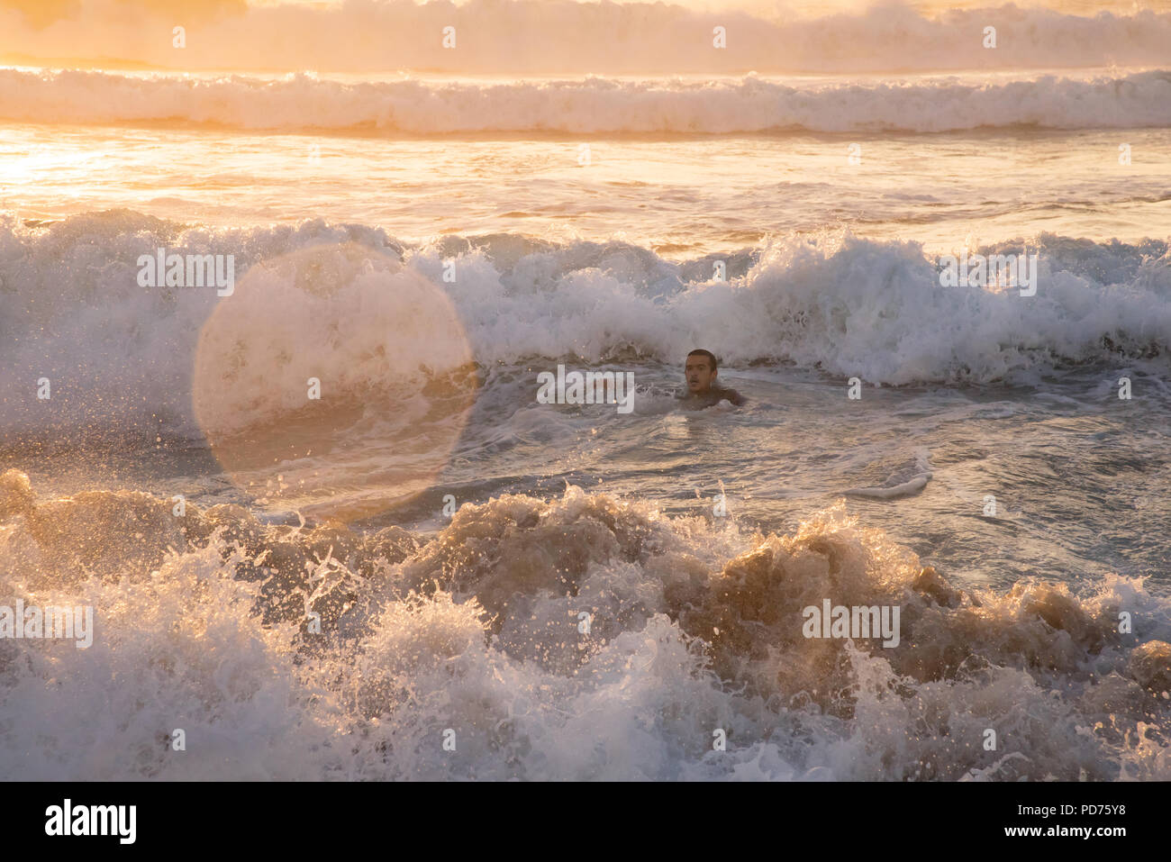 The head of a handsome young man poking above the waves in the ocean at ...