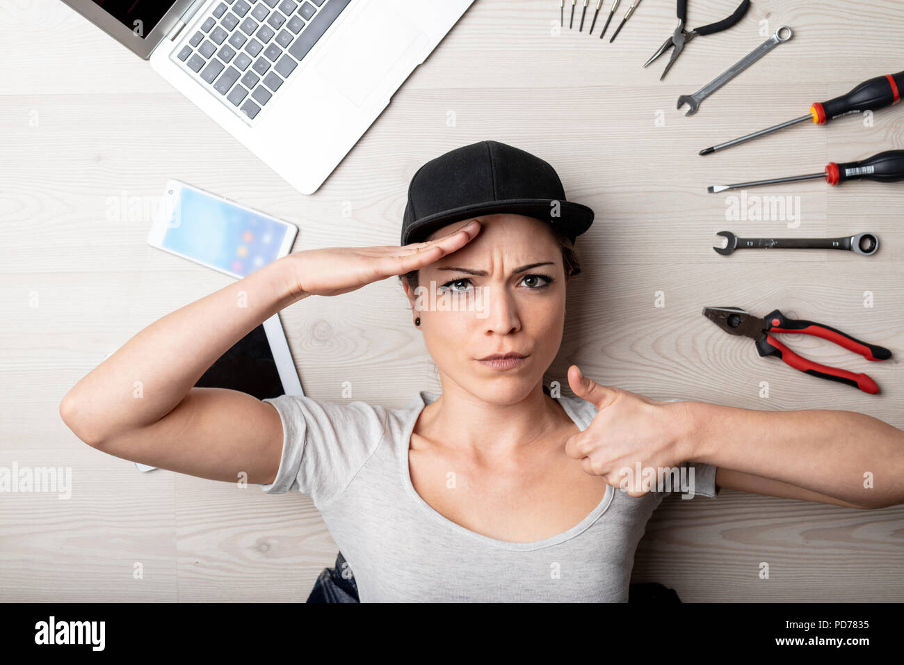 Capable young woman saluting the camera and giving a thumbs up as she ...