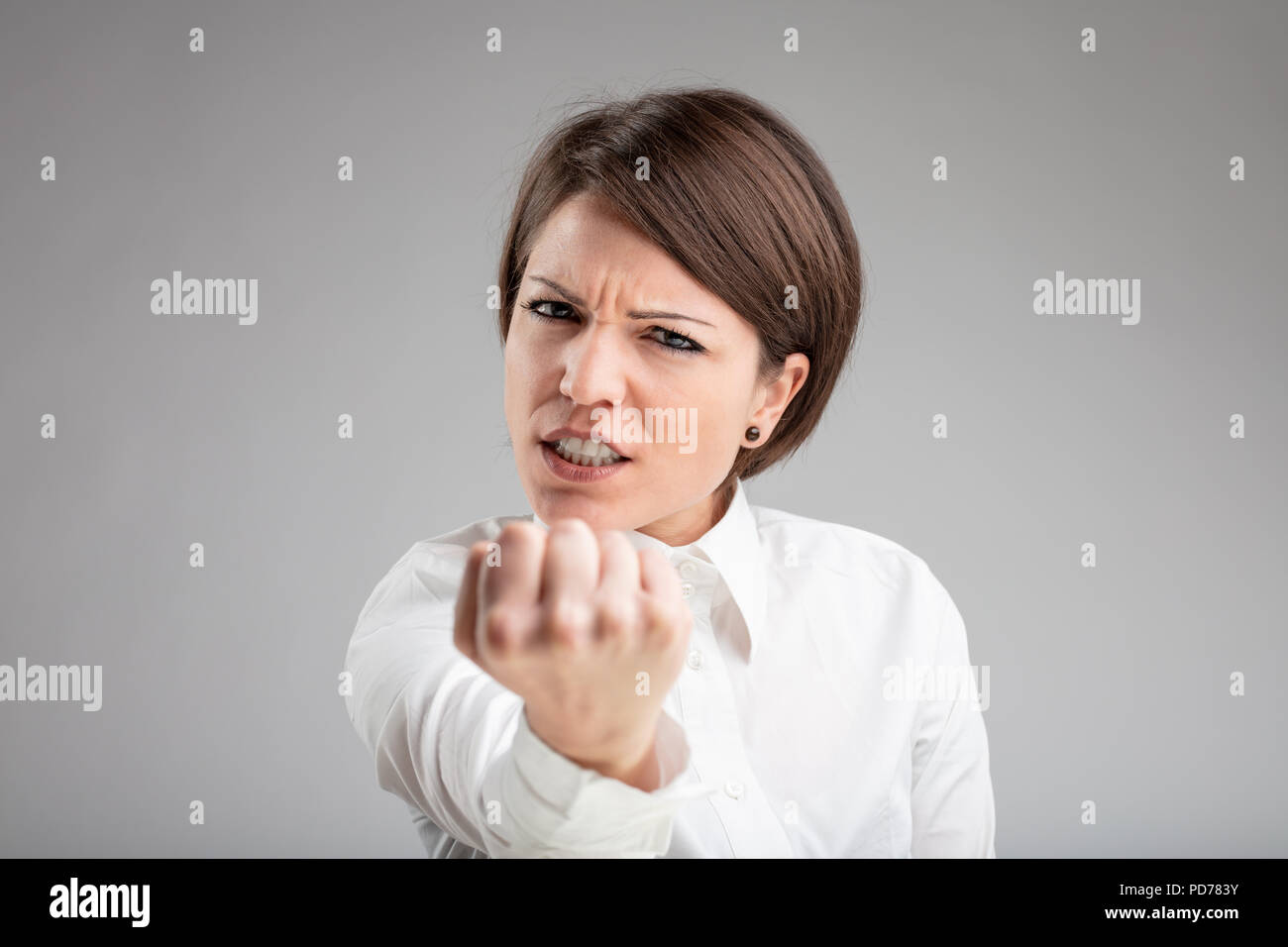 Angry woman shaking her fist at the camera while gnashing her teeth ...