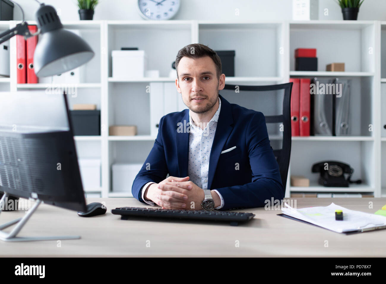A young man is sitting at the computer desk in the office Stock Photo ...