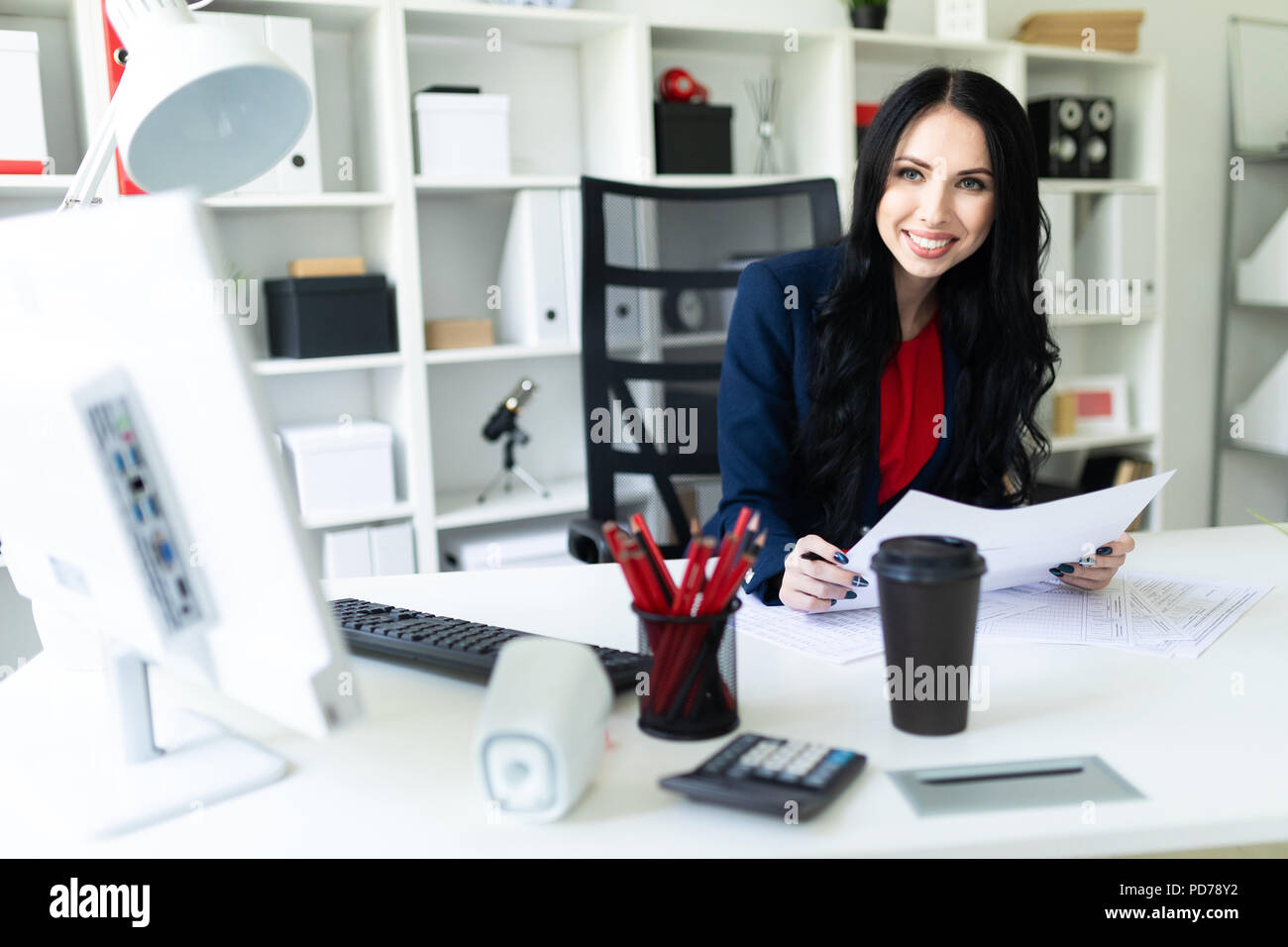 Beautiful young girl working with computer and documents in the office ...