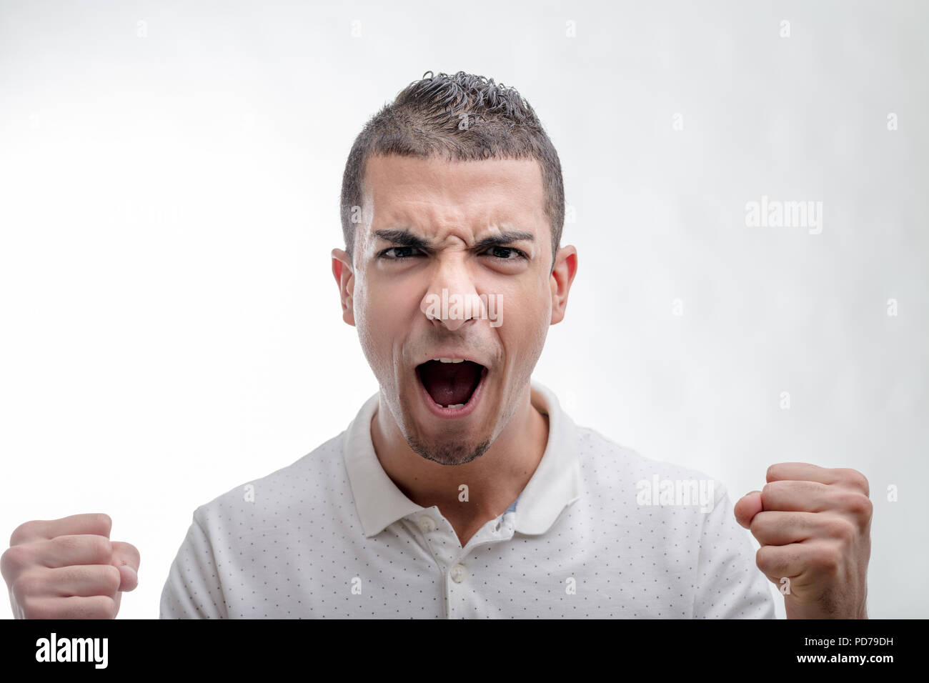 Emotional man yelling and clenching his fists as he glares at the ...