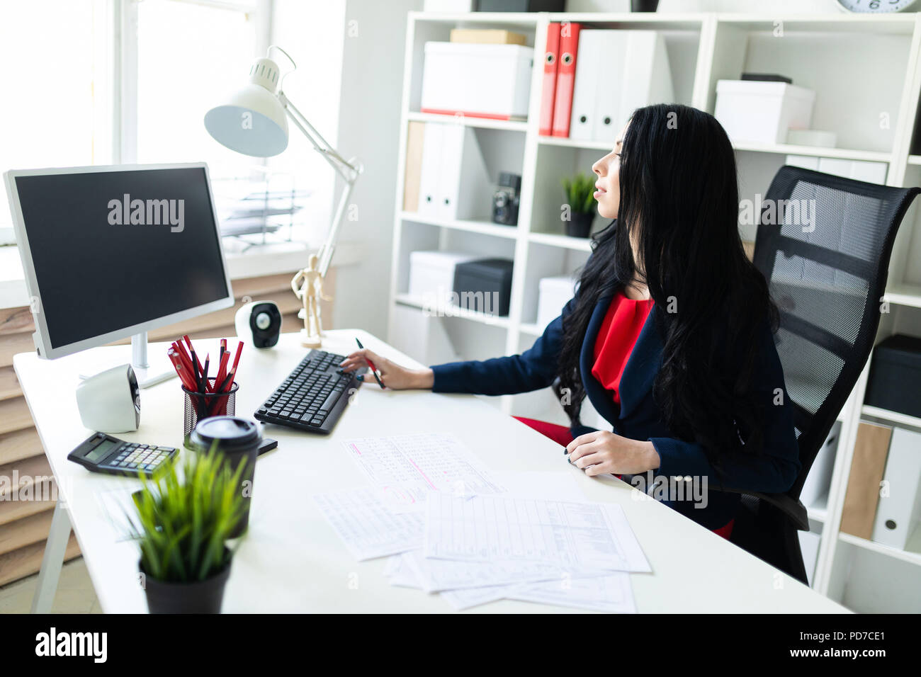 Beautiful young girl working with computer and documents in the office ...