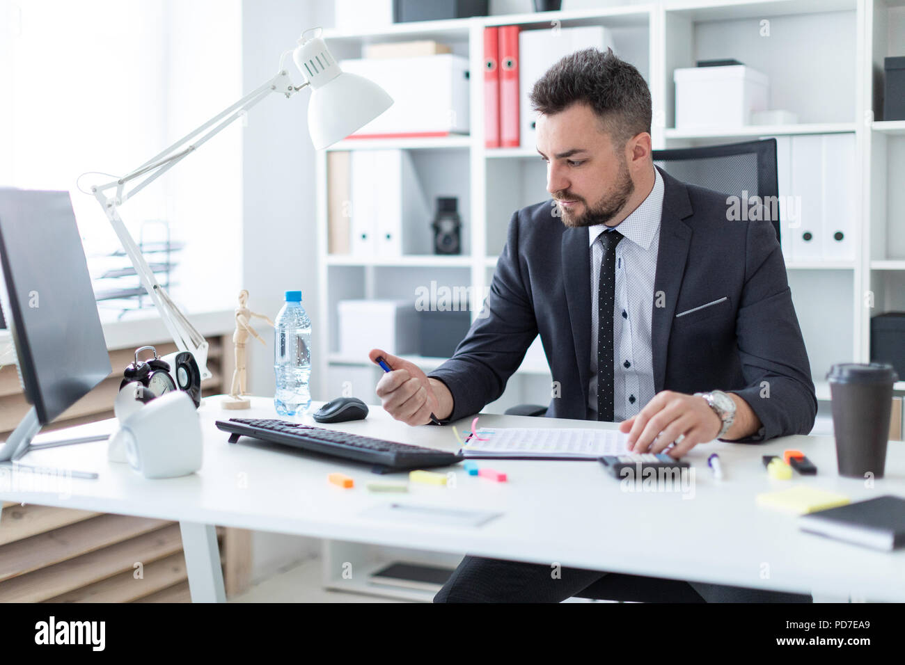A man sits at the office at the table and clicks a pen Stock Photo - Alamy