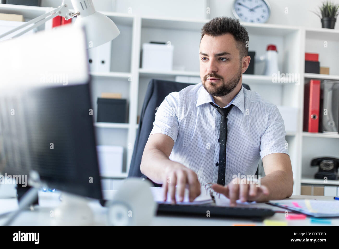 A man is sitting at a table in the office, working with documents and a ...