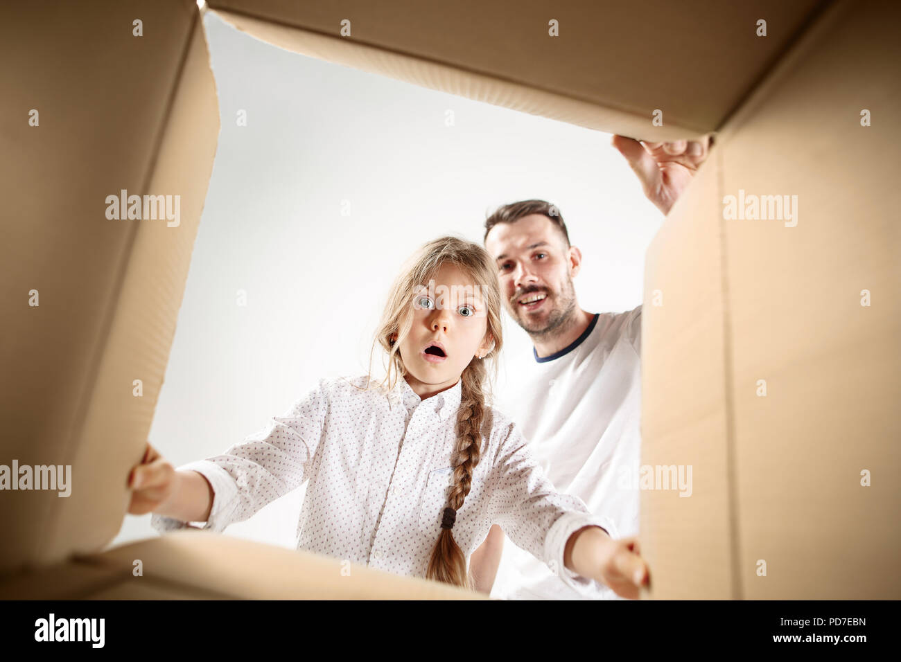 The surprised dad with daughter unpacking, opening carton box and ...