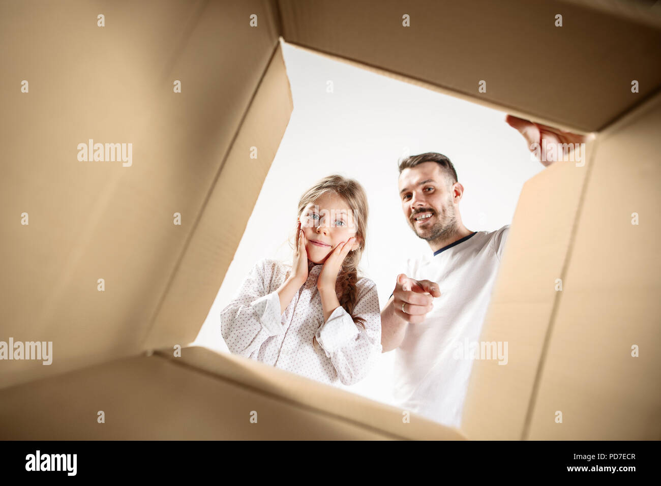 The surprised dad with daughter unpacking, opening carton box and ...