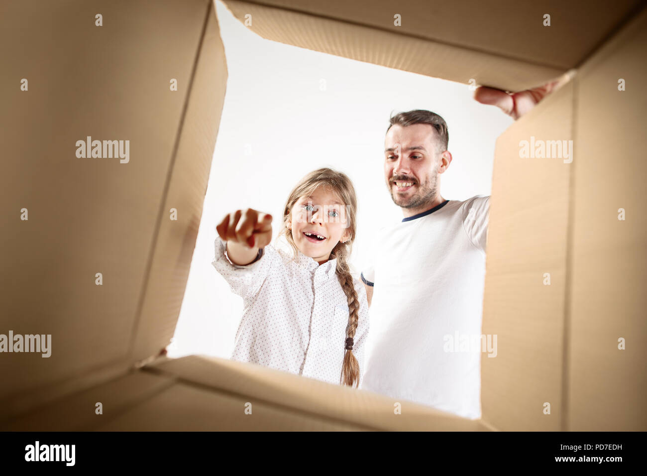 The surprised dad with daughter unpacking, opening carton box and ...