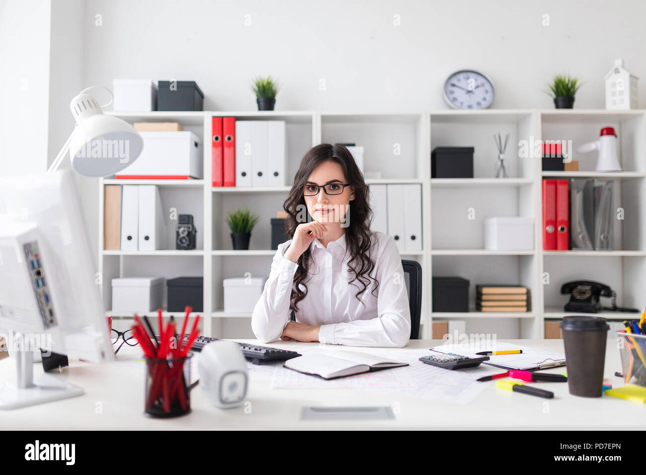 Beautiful young girl is sitting at the table in the office Stock Photo ...