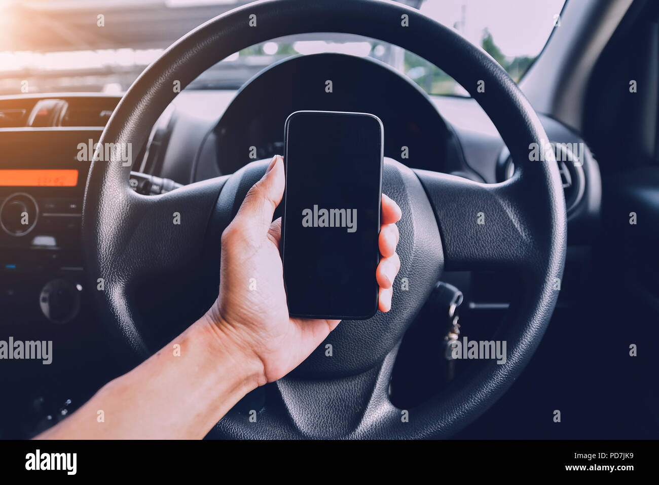 Hand holding smartphone in car parked on street.And using smartphone to ...