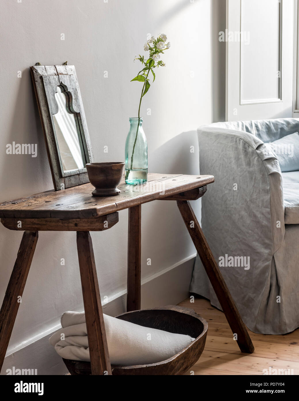 Rustic stool in bedroom next to small armchair upholstered in linen ...