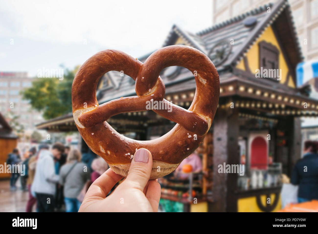 A girl or a young woman is holding a traditional German pretzel in the ...