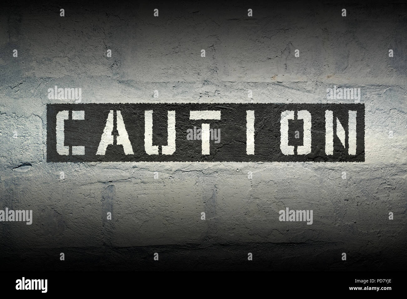 caution stencil print on the grunge white brick wall Stock Photo - Alamy