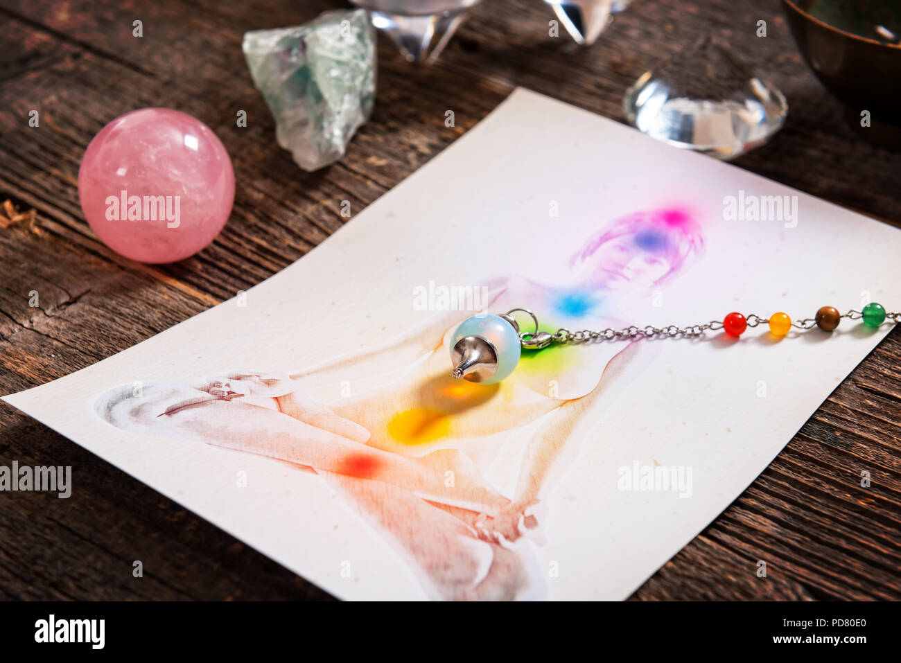 Chakras illustrated over human body with natural crystals and pendulum ...
